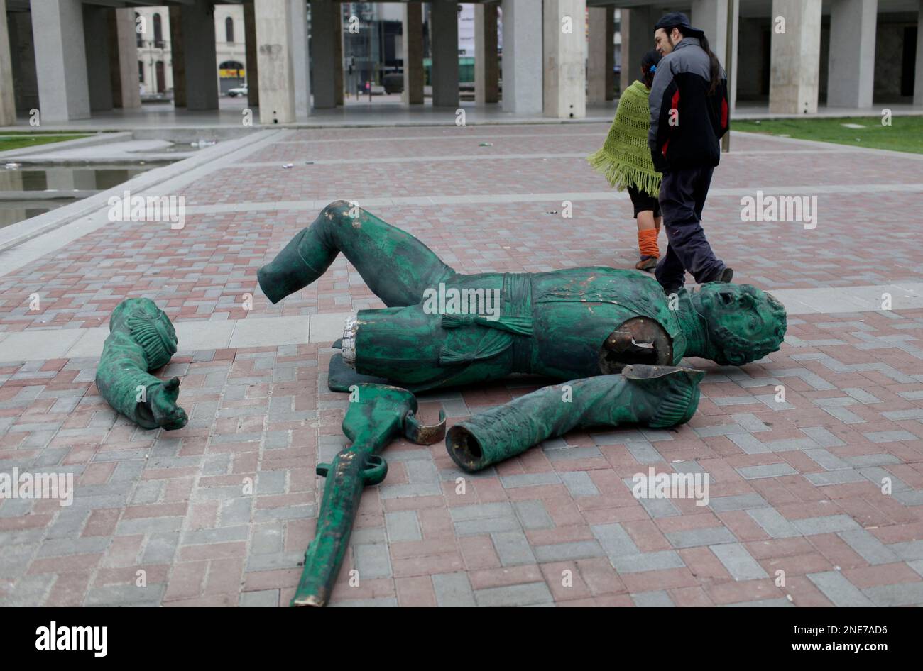 A couple walks past a destroyed statue of Chile's National Hero ...