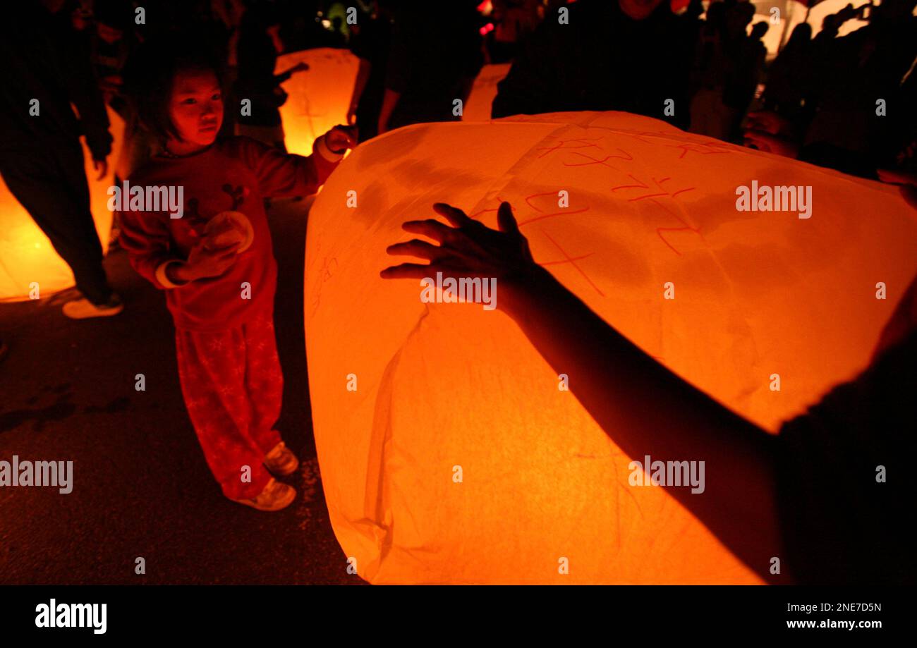 A young Taiwanese girl prepares to launch a lantern in the sky to ...