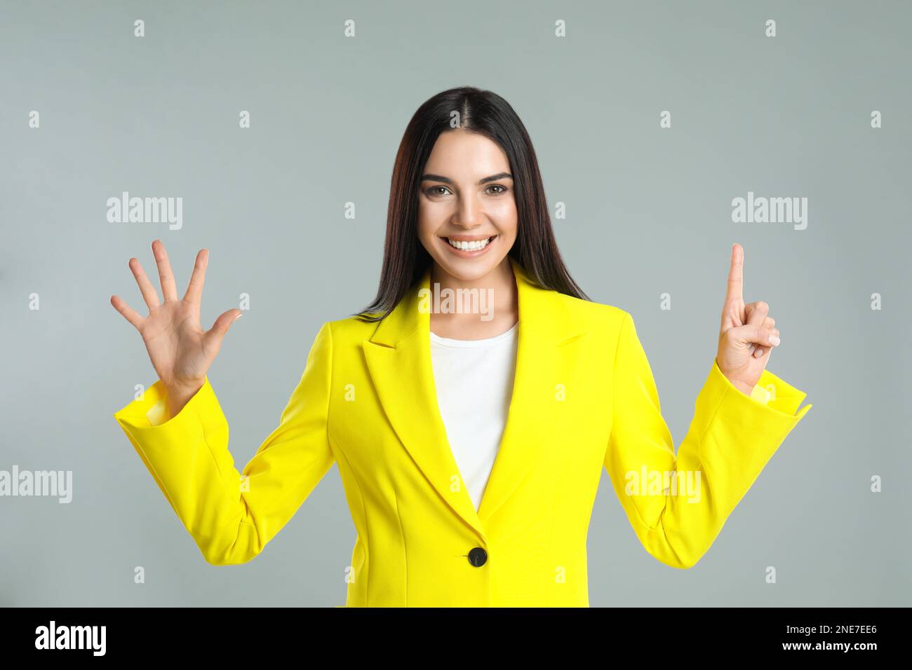 Woman showing number six with her hands on grey background Stock Photo ...