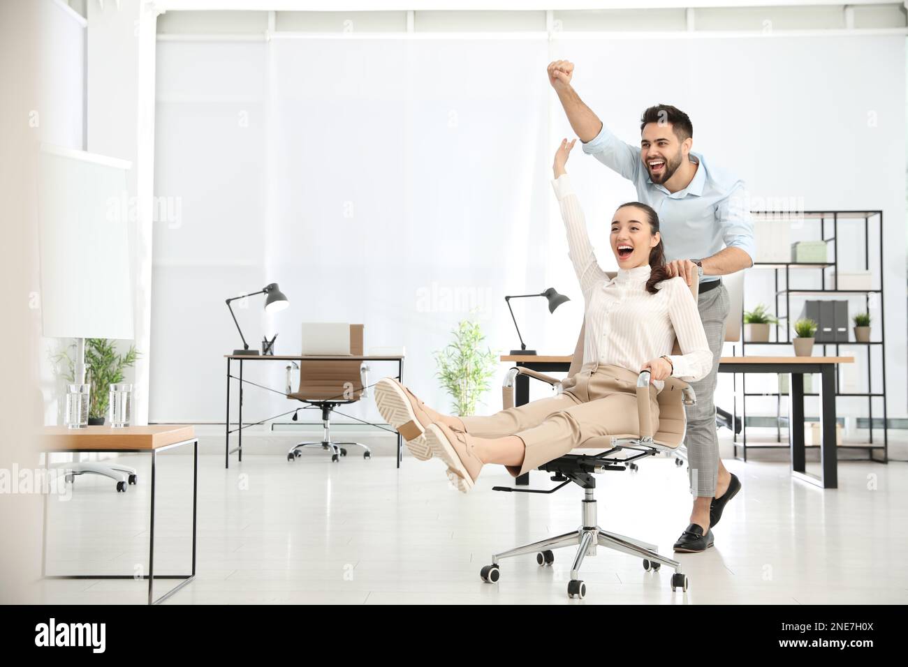 Office employee giving his colleague ride in chair at workplace. Space ...