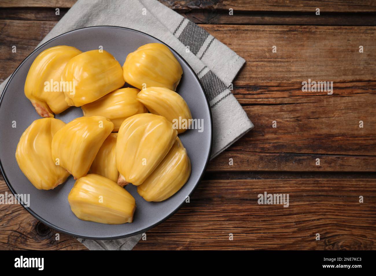 Delicious exotic jackfruit bulbs on wooden table, top view. Space for ...