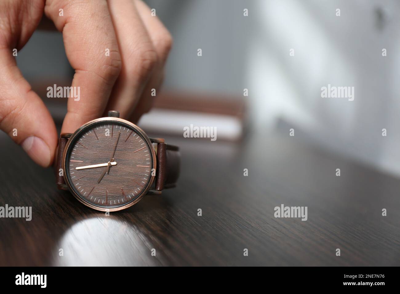 Man putting luxury wrist watch on table, closeup. Space for text Stock ...