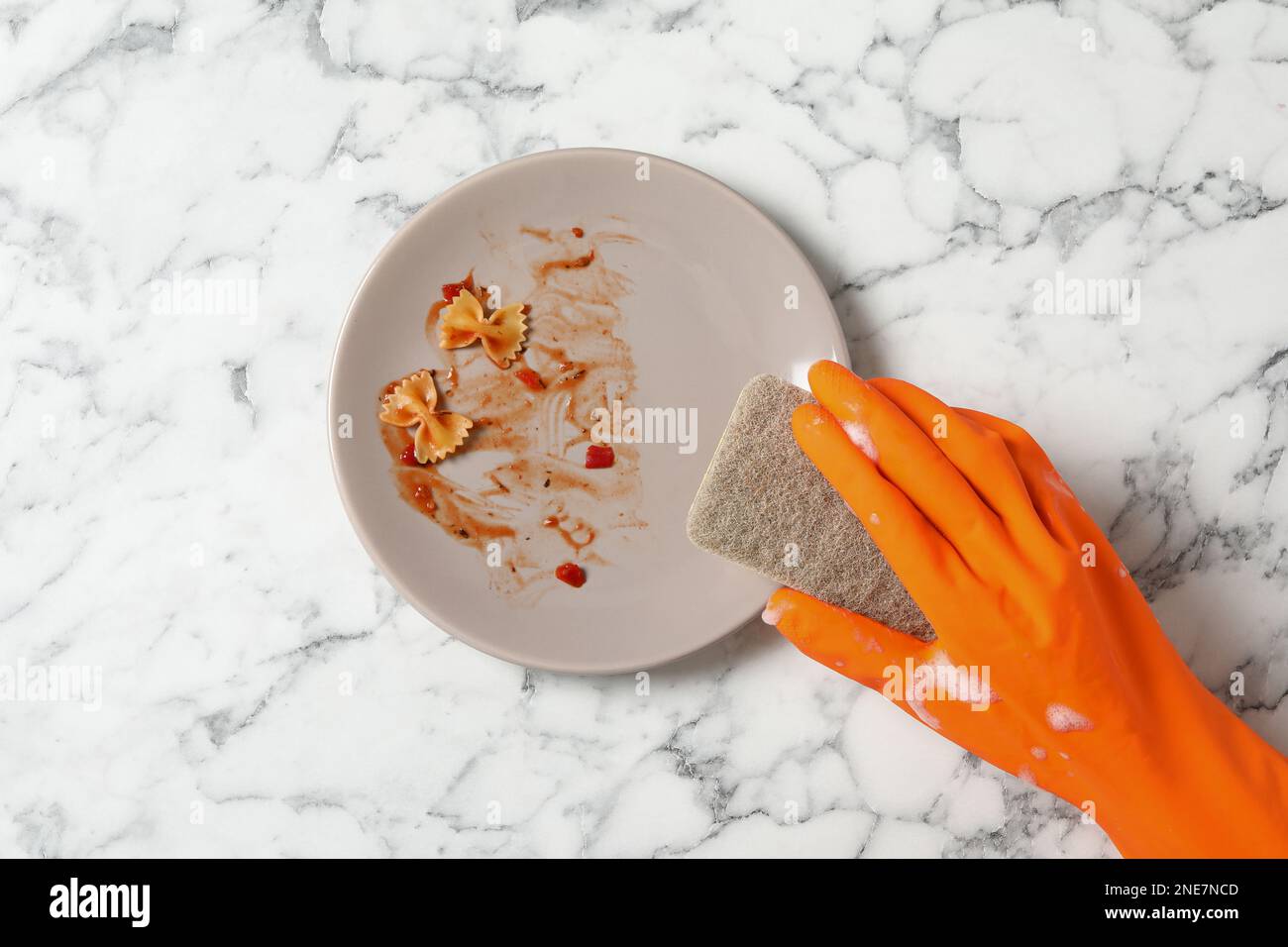 Woman washing dirty plate at white marble table, top view Stock Photo ...