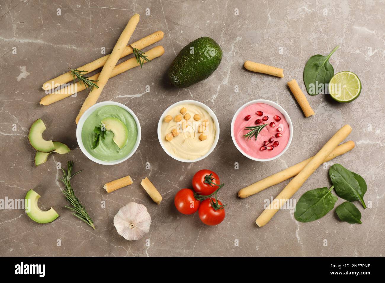 Flat lay composition with different delicious hummuses on brown marble ...
