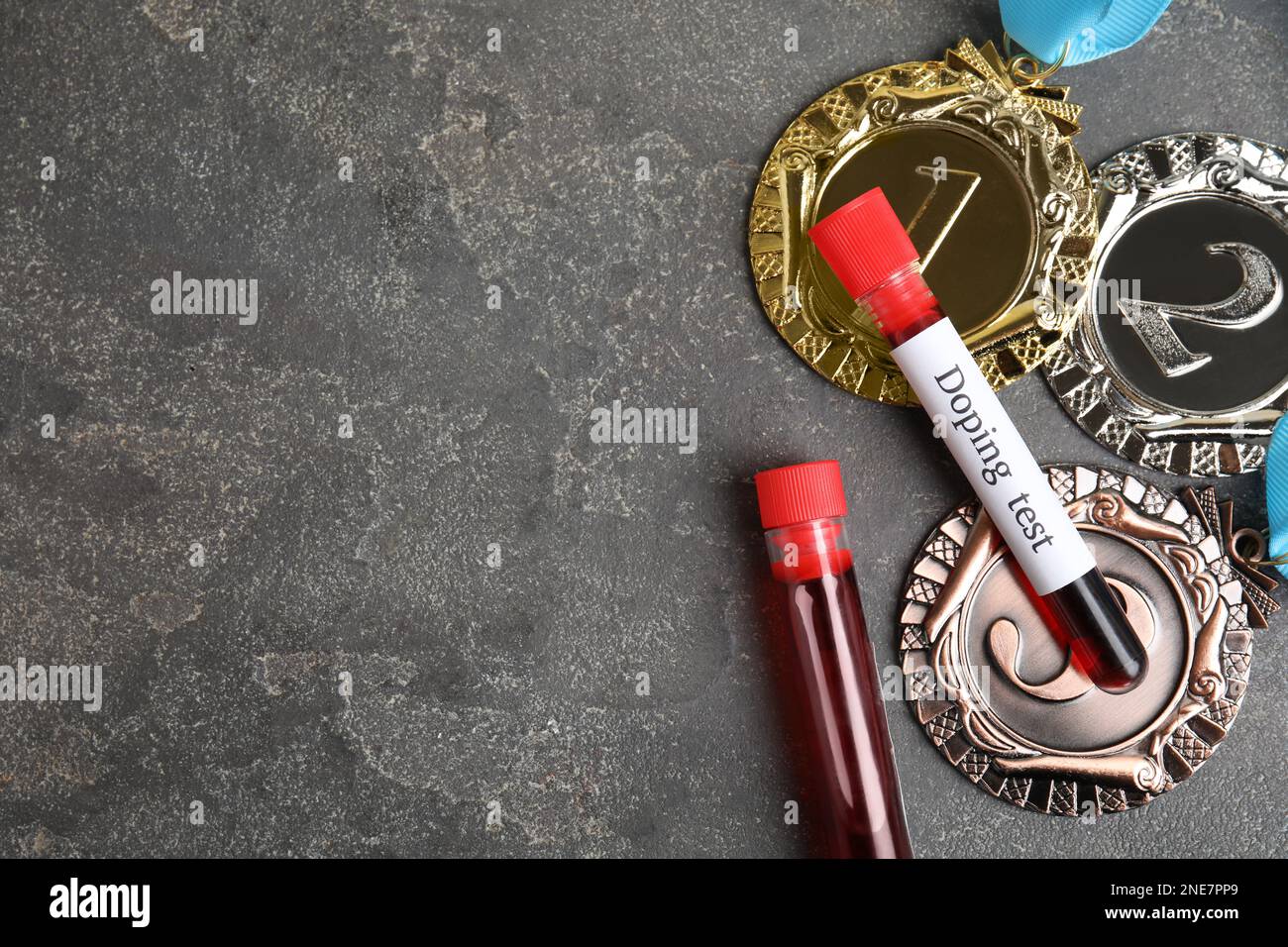 Medals and tubes of blood with words Doping test on grey stone table ...
