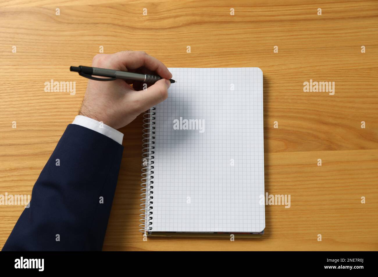 Left-handed man writing in notebook at wooden desk, top view Stock ...