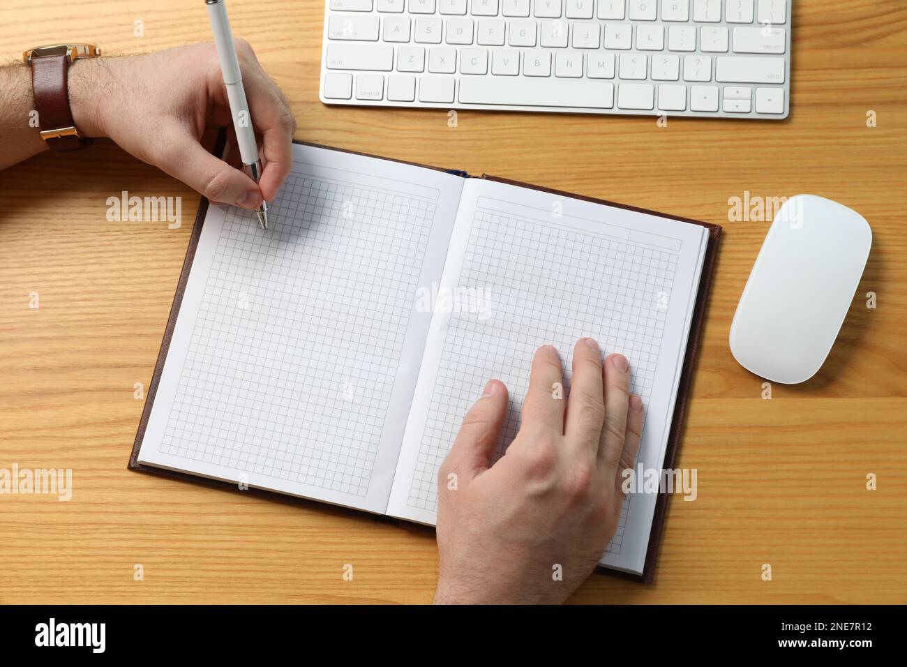 Left-handed man writing in notebook at wooden desk, top view Stock ...