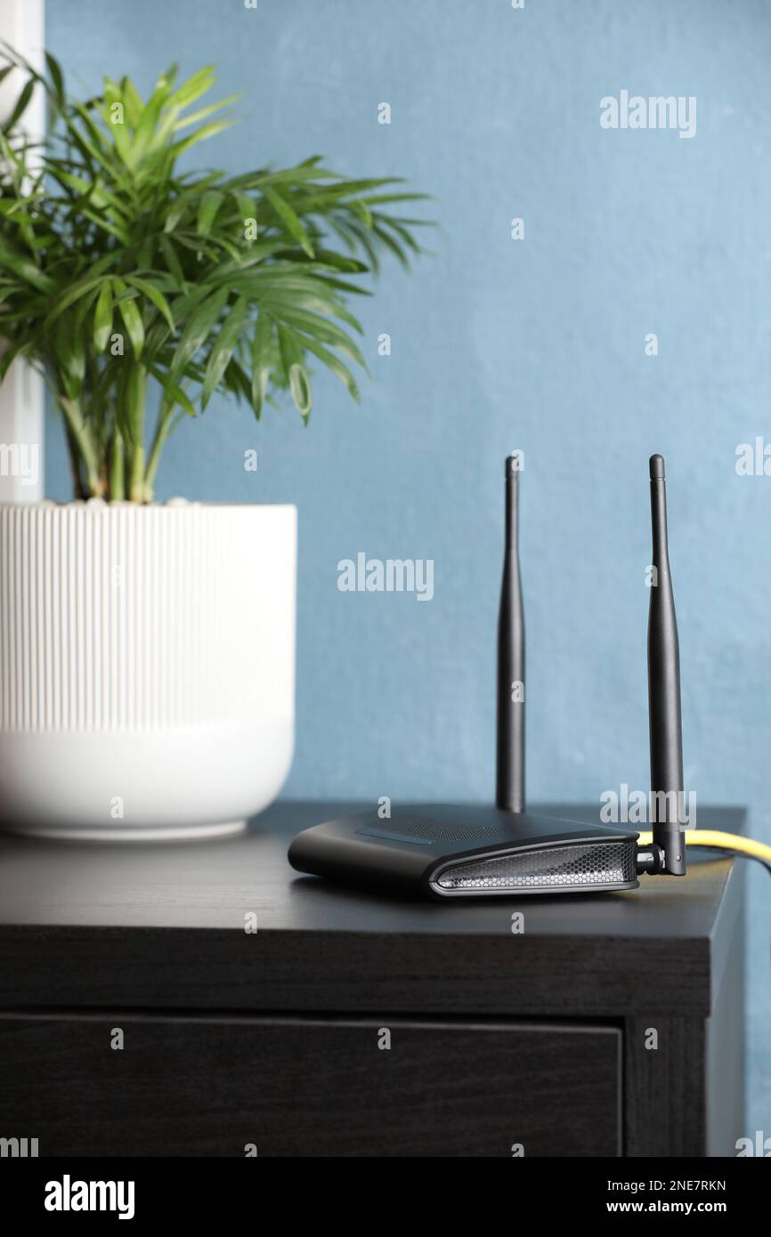 Modern Wi-Fi router near blue wall indoors Stock Photo - Alamy