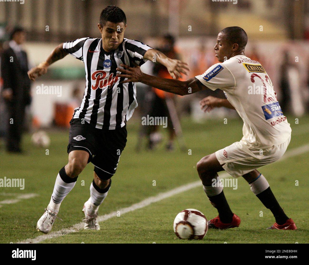 Paraguay's Libertad's Victor Hugo Ayala, left, fights for the ball with Peru's Universitario's ...