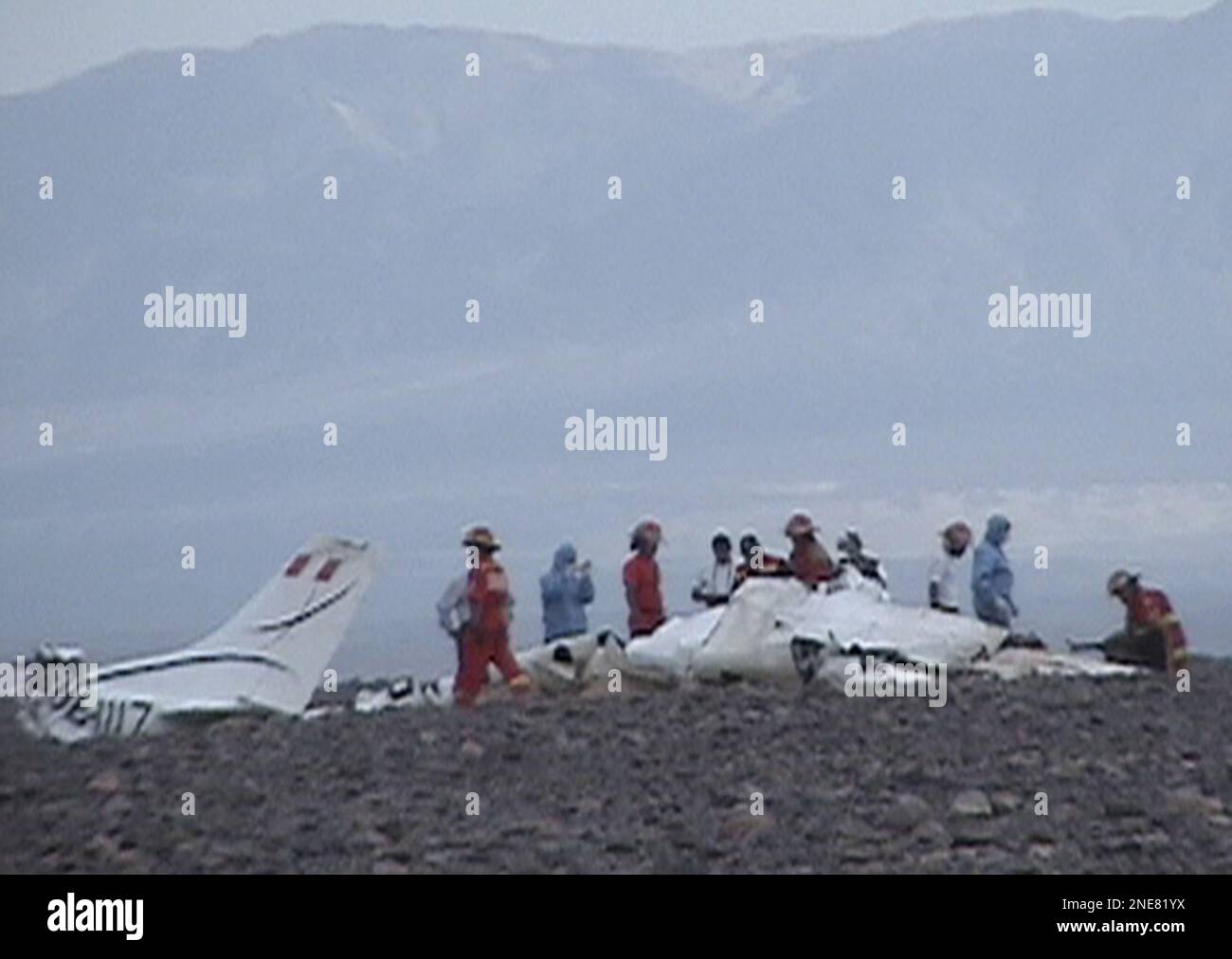 Firefighters stand near the remains of a plane crashed in Nazca, Peru ...
