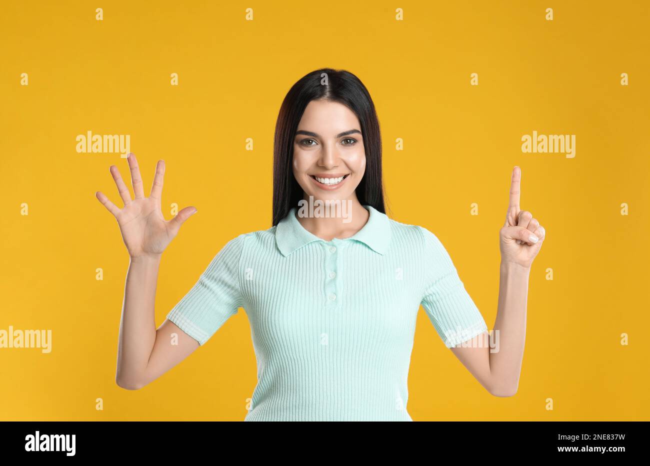 Woman showing number six with her hands on yellow background Stock ...
