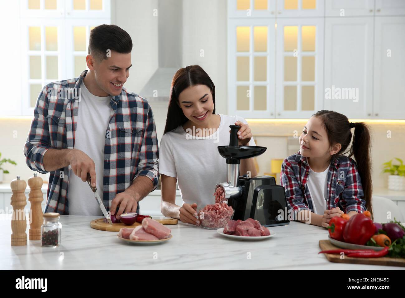 Happy family making dinner together in kitchen, woman using modern meat ...