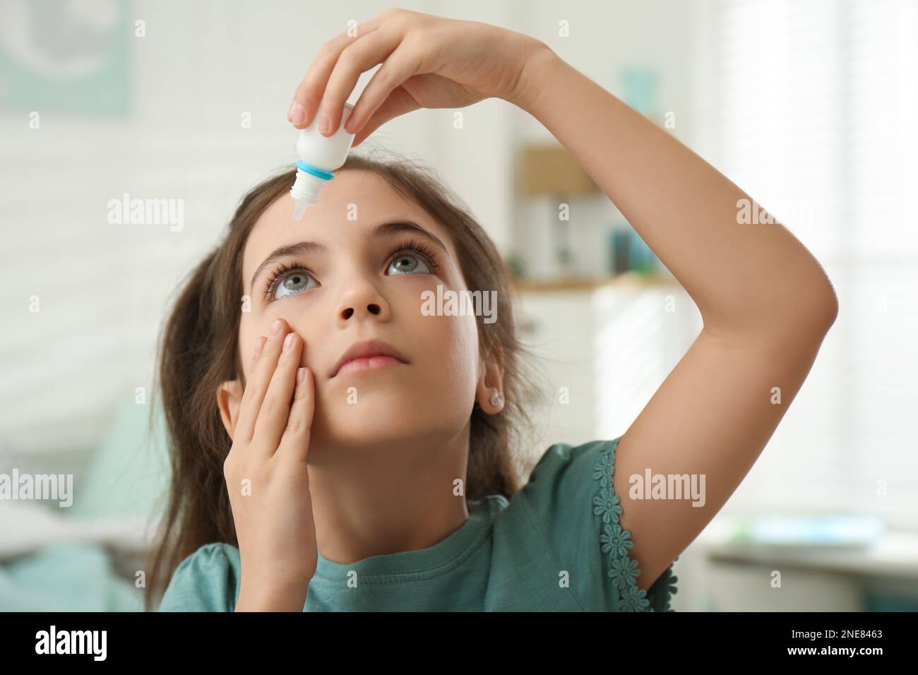 Adorable little girl using eye drops indoors Stock Photo - Alamy
