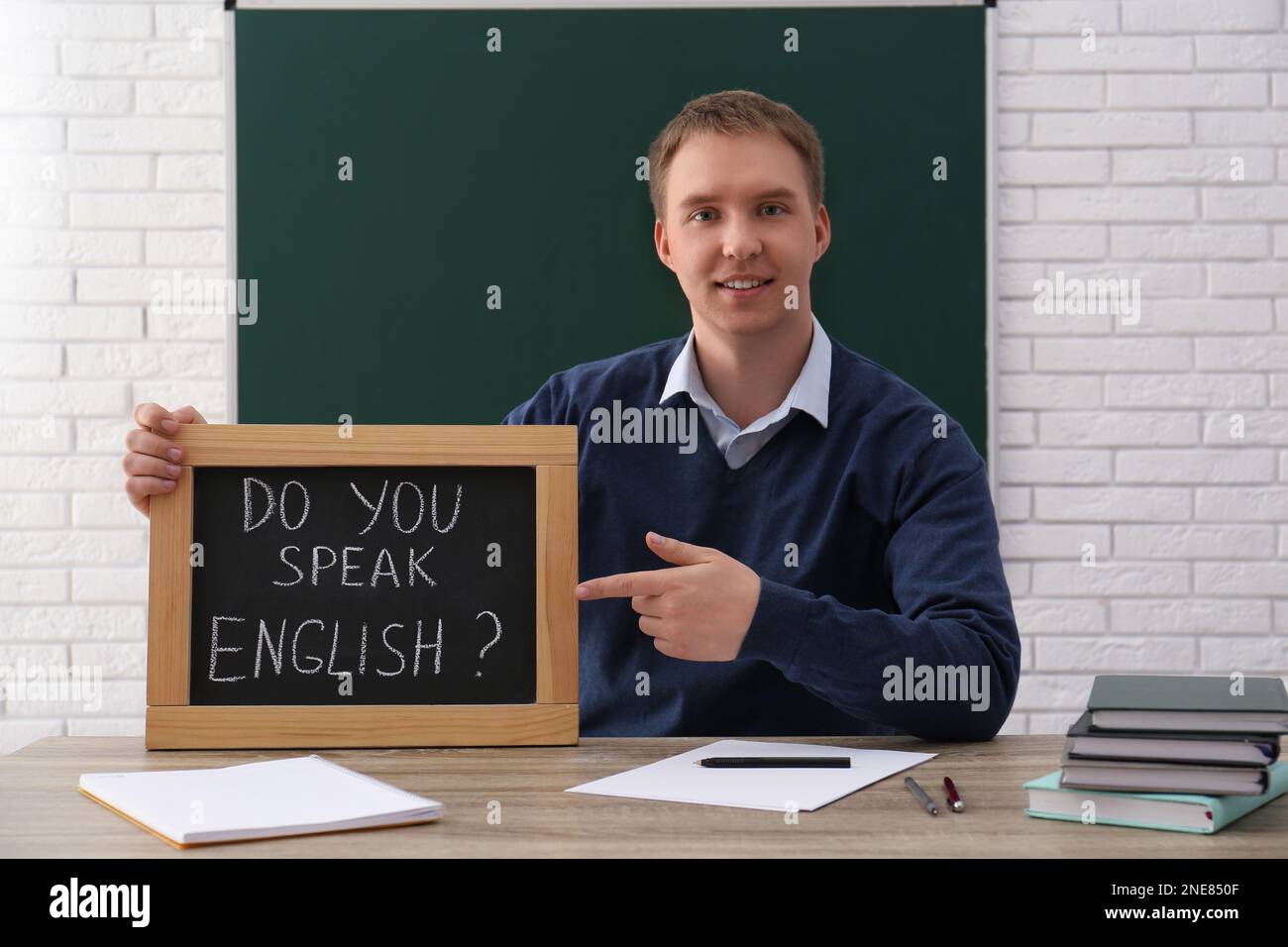 Teacher holding small chalkboard with inscription Do You Speak English ...