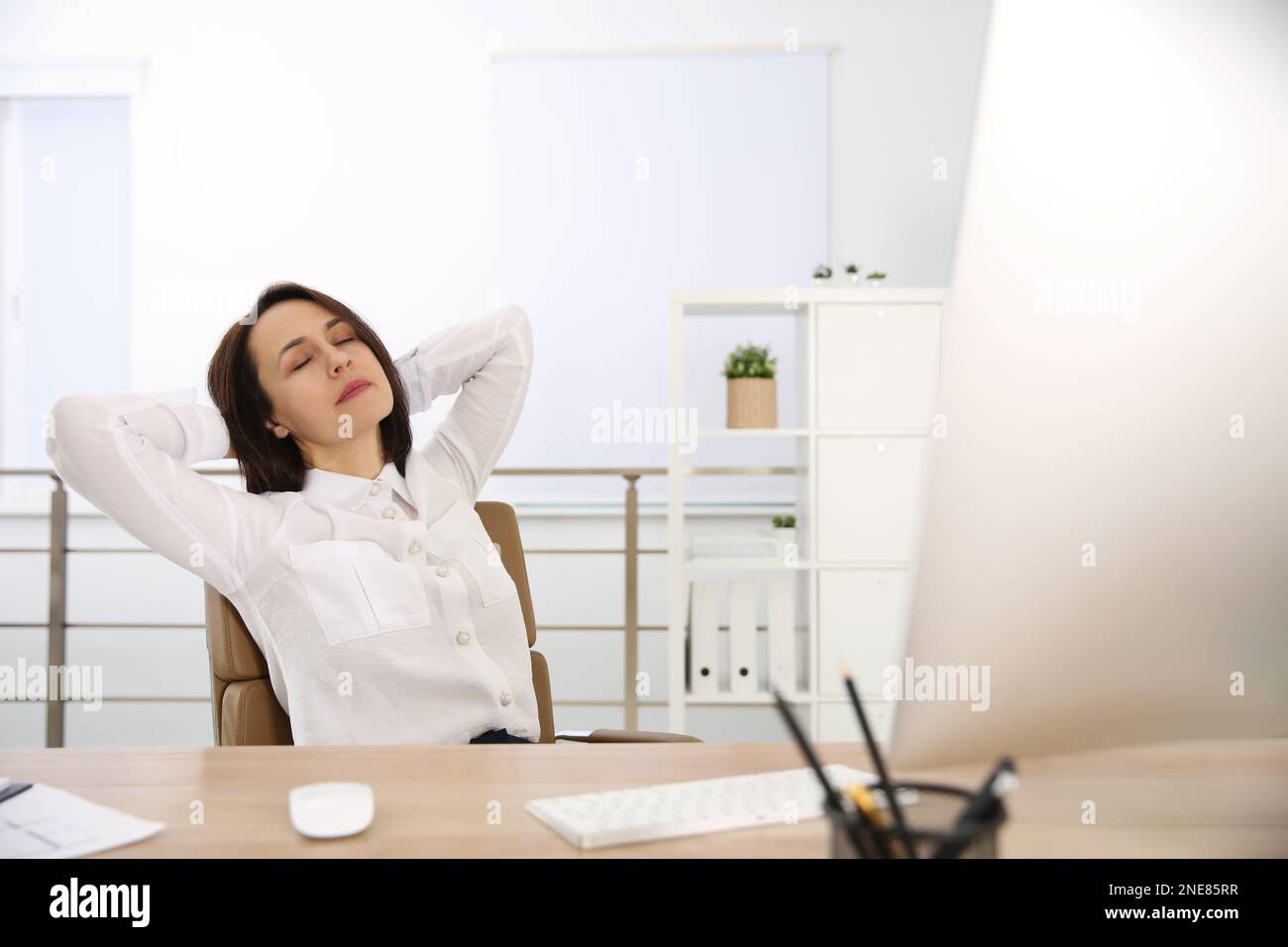Woman relaxing in office chair at workplace Stock Photo - Alamy