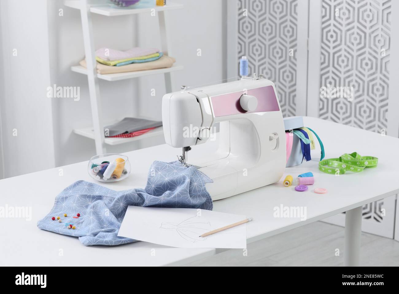 Modern sewing machine, fabric and accessories on table indoors Stock ...