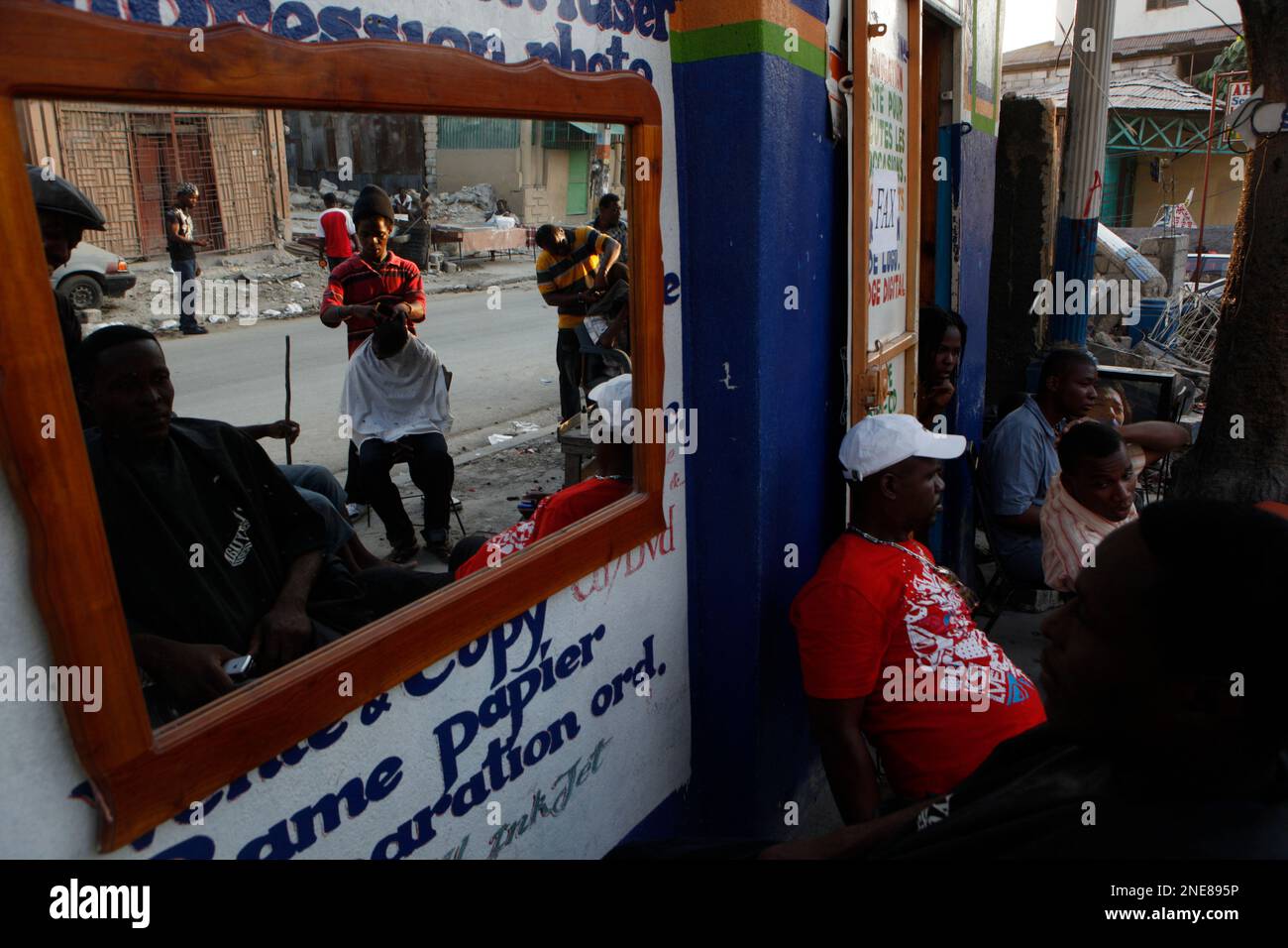Men get a haircut at a small barber shop set up in a street in downtown ...