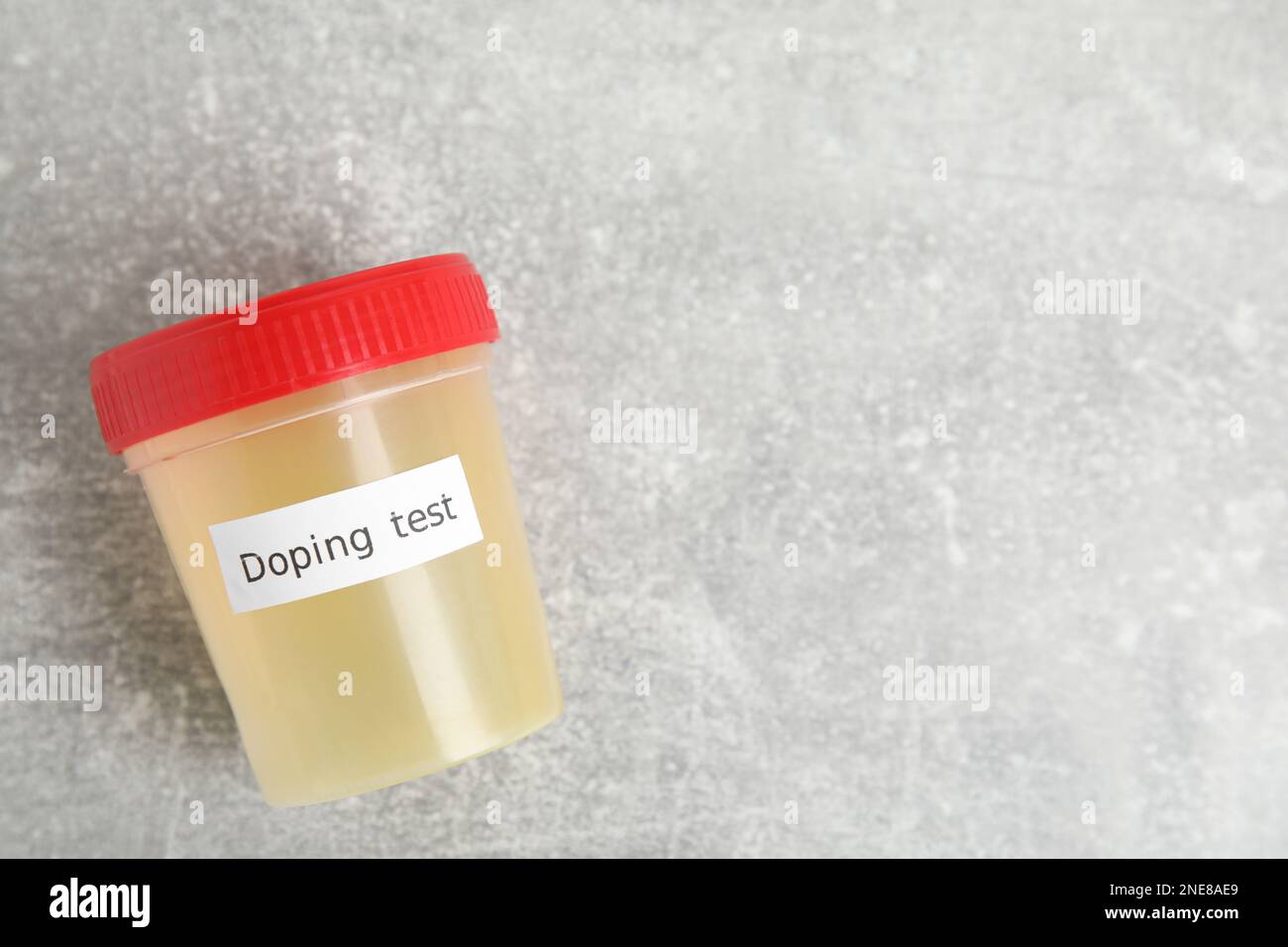Jar of urine with words Doping test on light grey stone table, top view ...