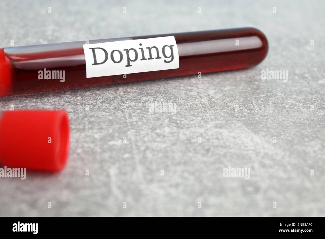 Tube of blood with word Doping on light grey stone table, closeup ...