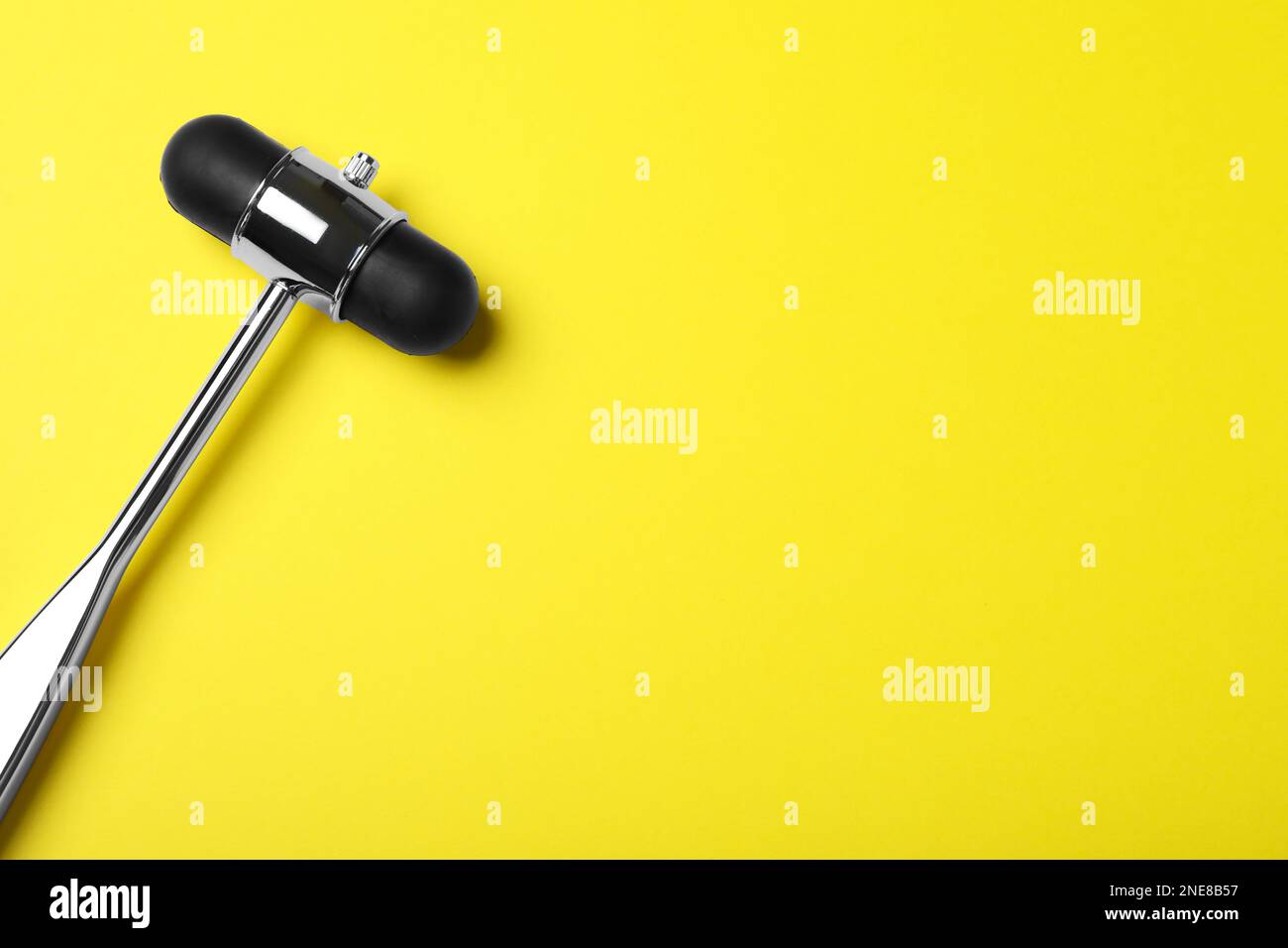 Reflex hammer on yellow background, top view with space for text ...