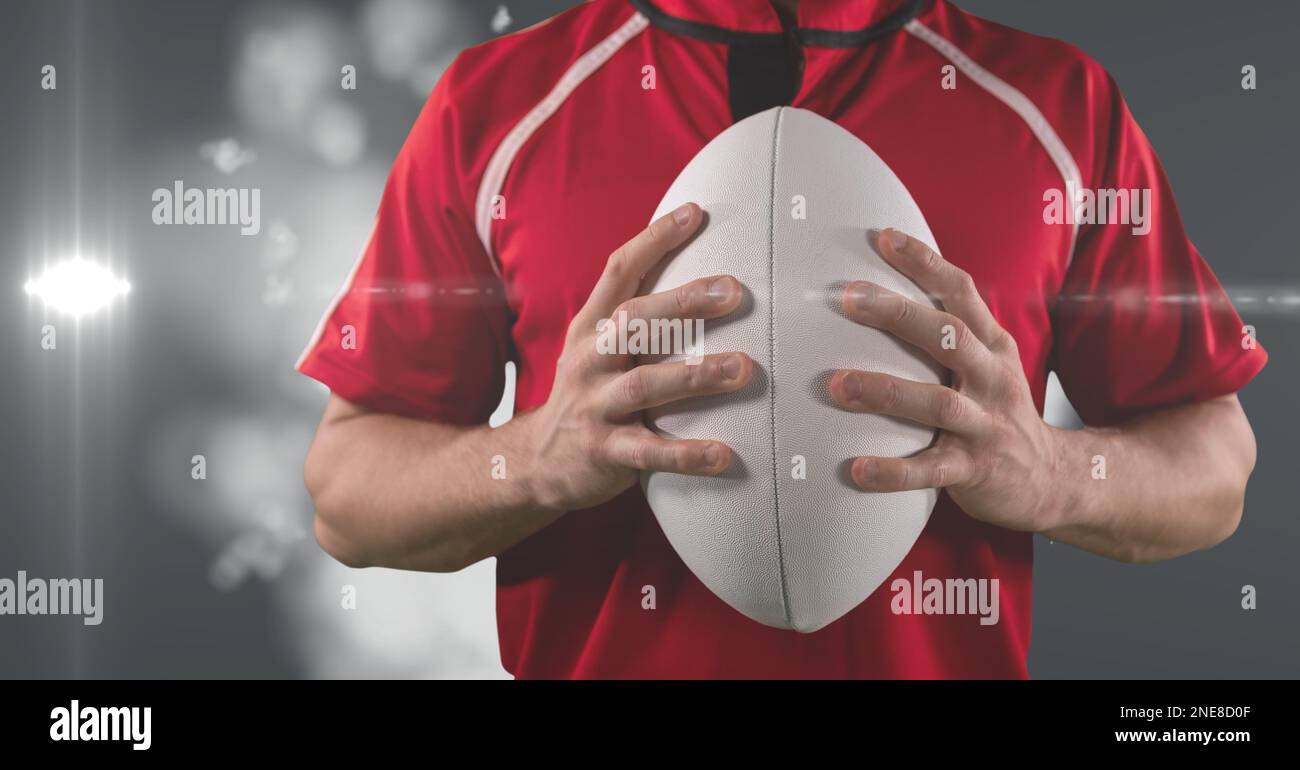 Mid section of caucasian male rugby player holding rugby ball against ...