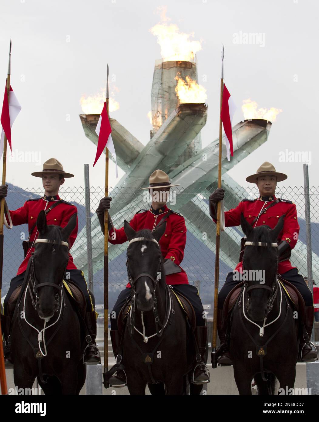 Members of the RCMP Musical Ride pose in front of the Olympic cauldron ...