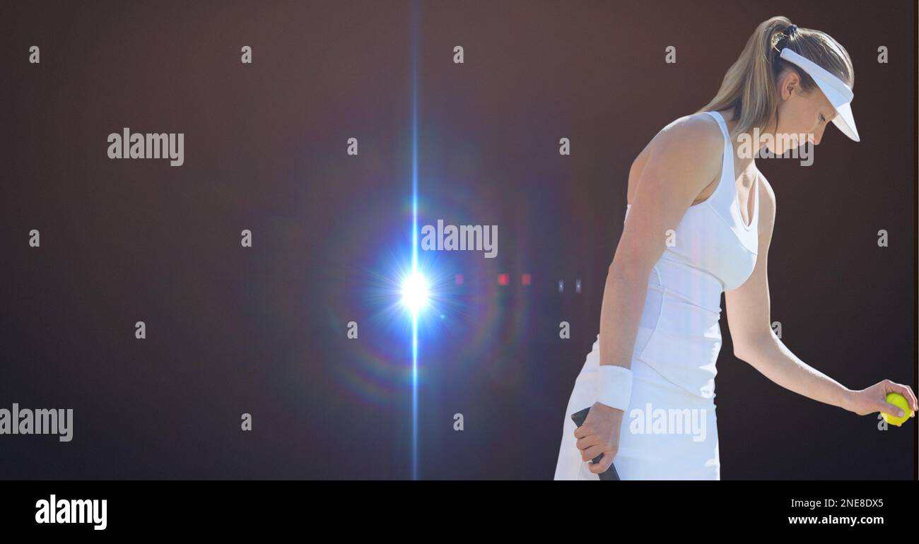 Caucasian female tennis player bouncing a ball against bright spot of ...