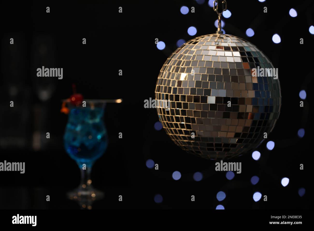 Shiny disco ball hanging over bar counter with cocktail in nightclub ...
