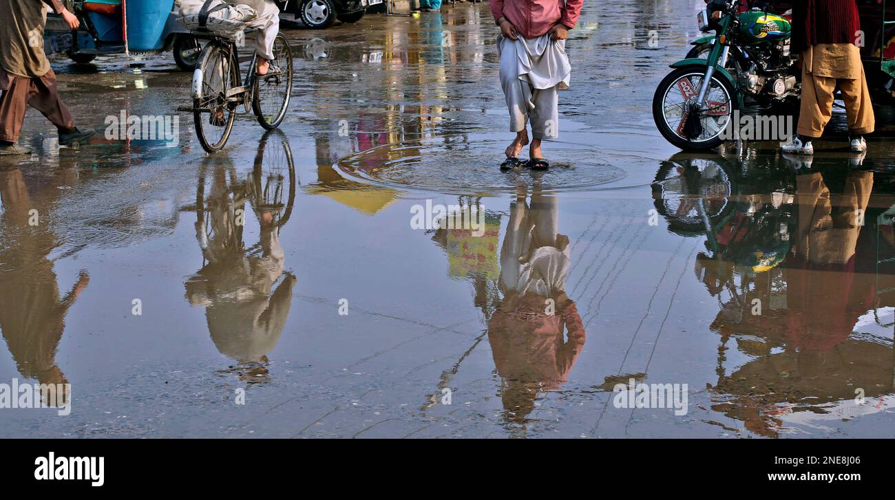 A Pakistani man, second from right, cleans his feet in a puddle of rain ...