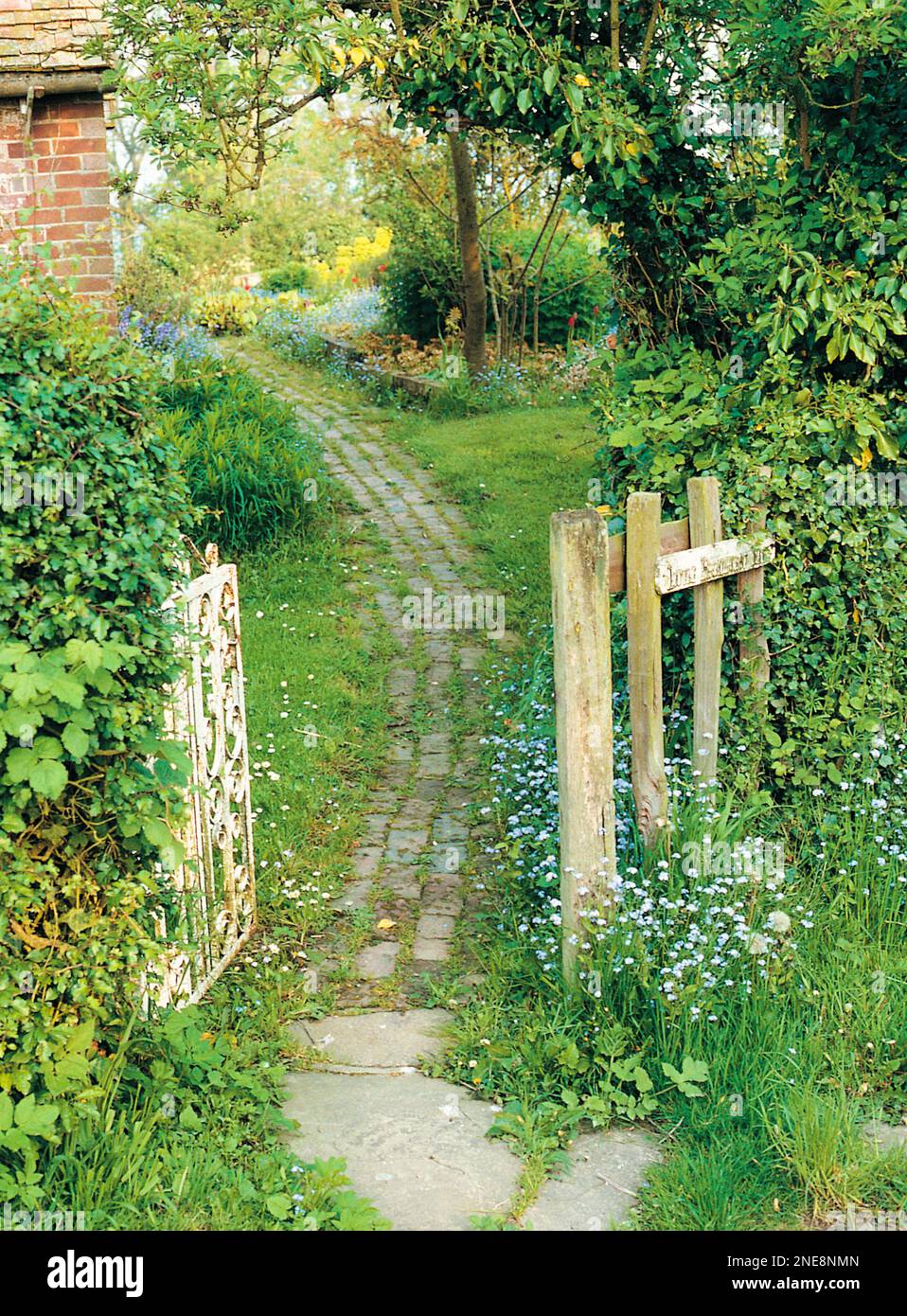 Cobbled pathway leading through open wooden gate into garden Stock ...