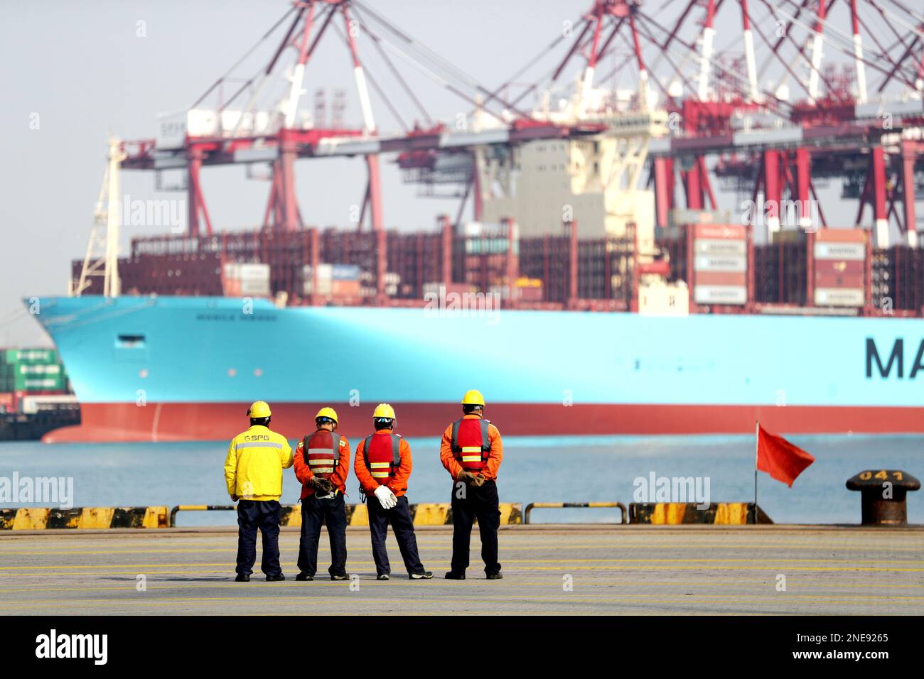 Port workers wait to serve a ship arriving at a container dockyard in ...