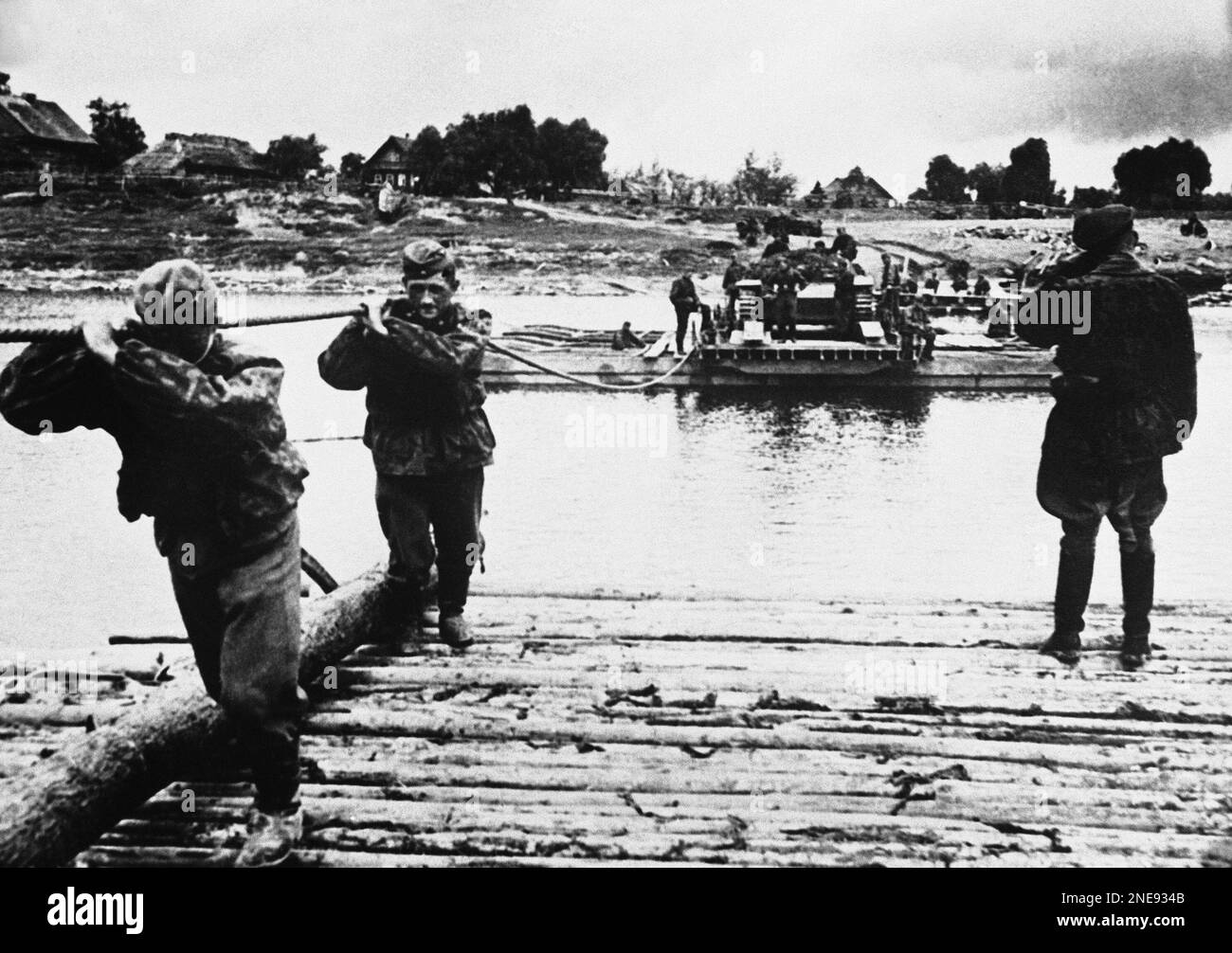 Nazi soldiers pulling a tank on a Pontoon bridge across a river in ...