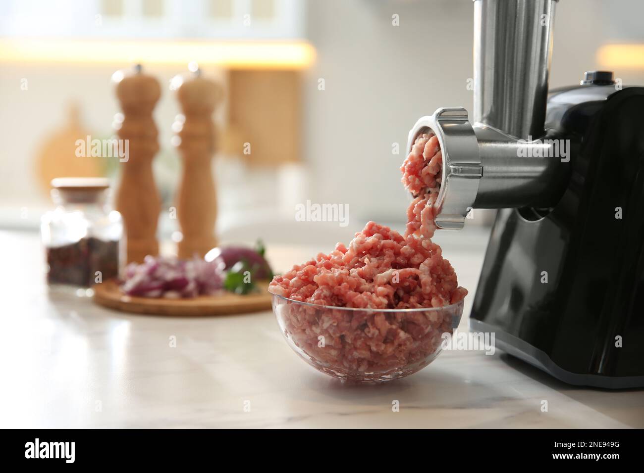 Modern meat grinder and products on white marble table in kitchen ...