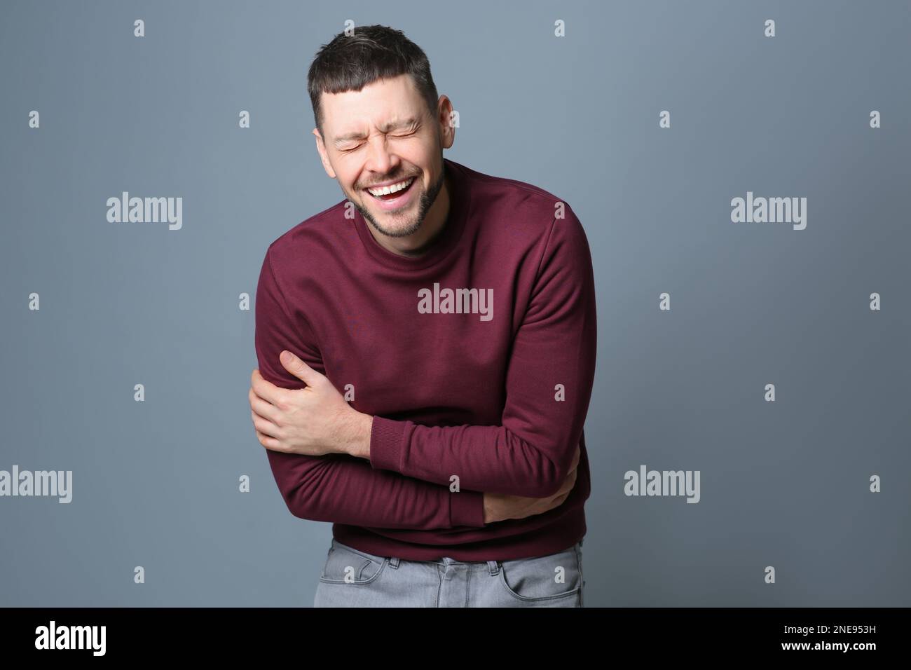 Handsome man laughing on grey background. Funny joke Stock Photo - Alamy