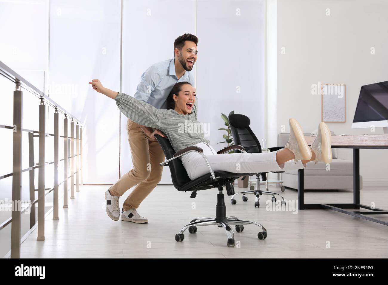Office employee giving his colleague ride in chair at workplace Stock ...