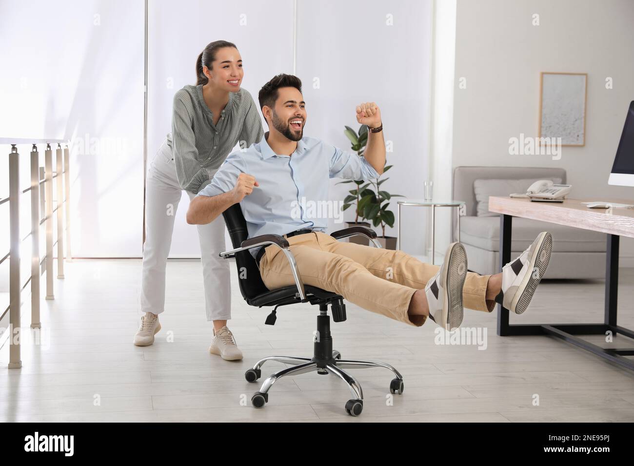 Office employee giving her colleague ride in chair at workplace Stock ...