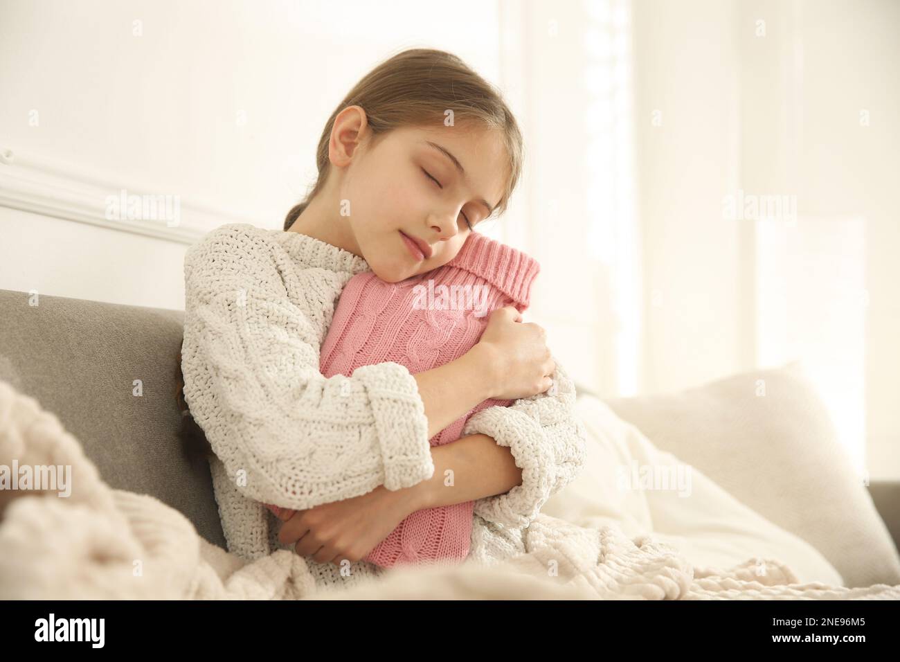 Ill girl with hot water bottle suffering from cold at home Stock Photo ...