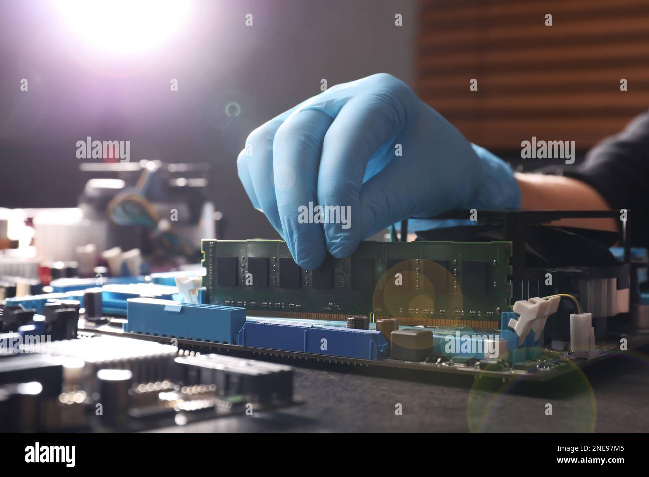 Technician repairing computer motherboard at table, closeup. Electronic ...