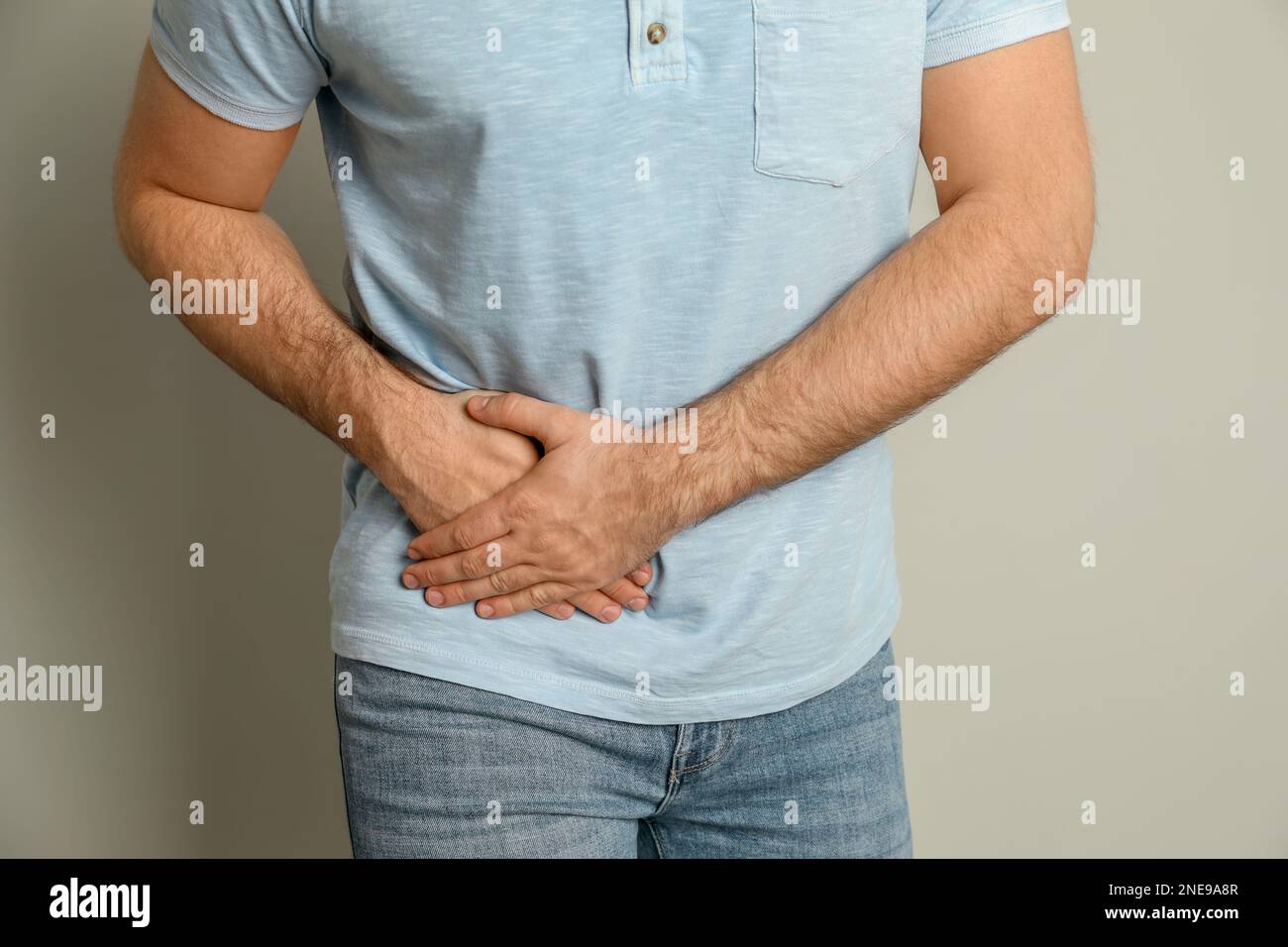 Man suffering from acute appendicitis on light grey background, closeup ...