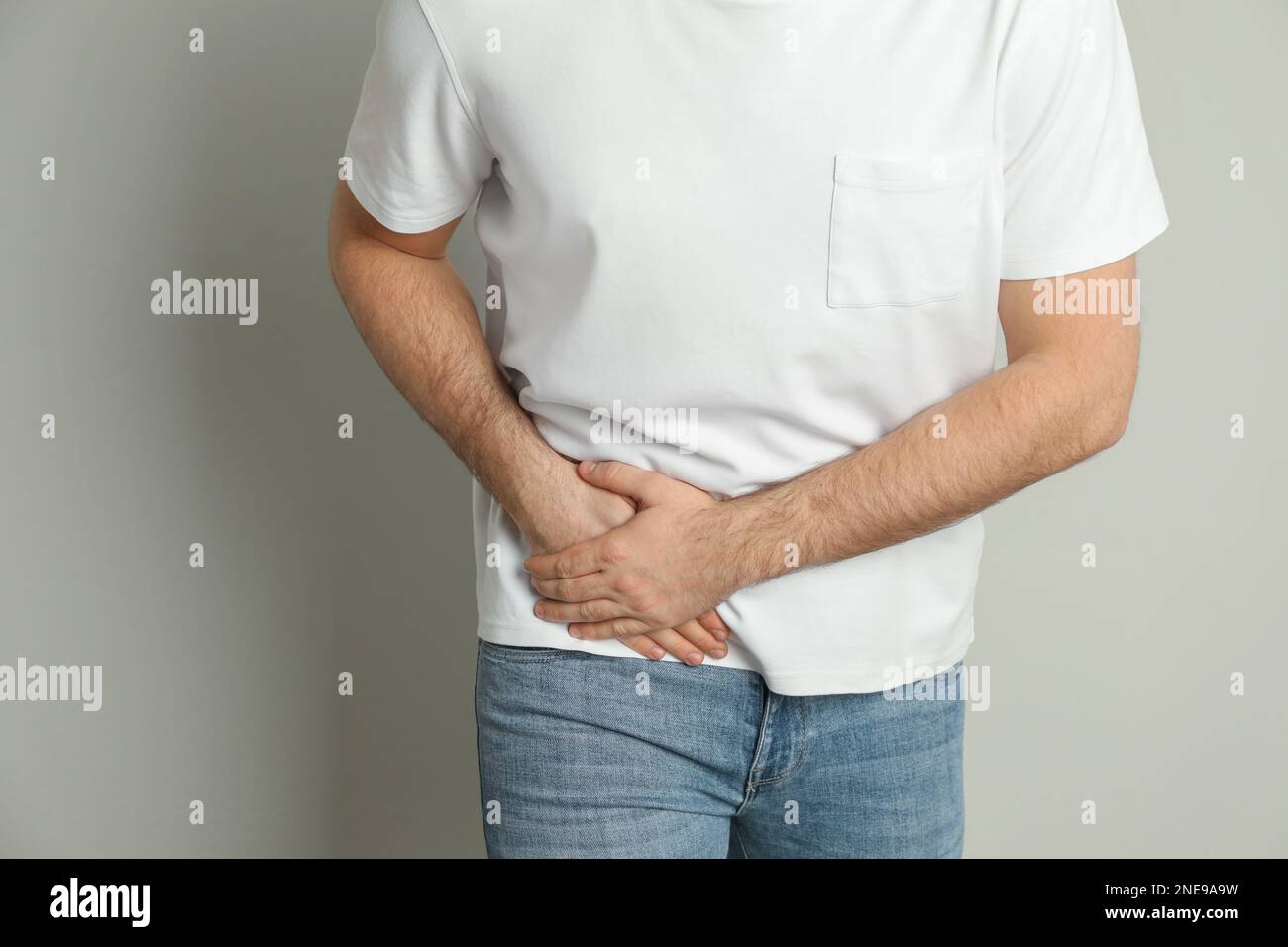 Man suffering from acute appendicitis on light grey background, closeup ...