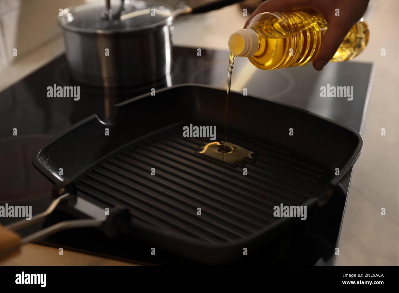 Man pouring cooking oil into frying pan in kitchen, closeup Stock Photo ...
