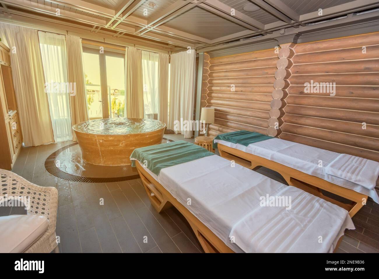Interior of spa and massage room with two beds and bath with view of ...