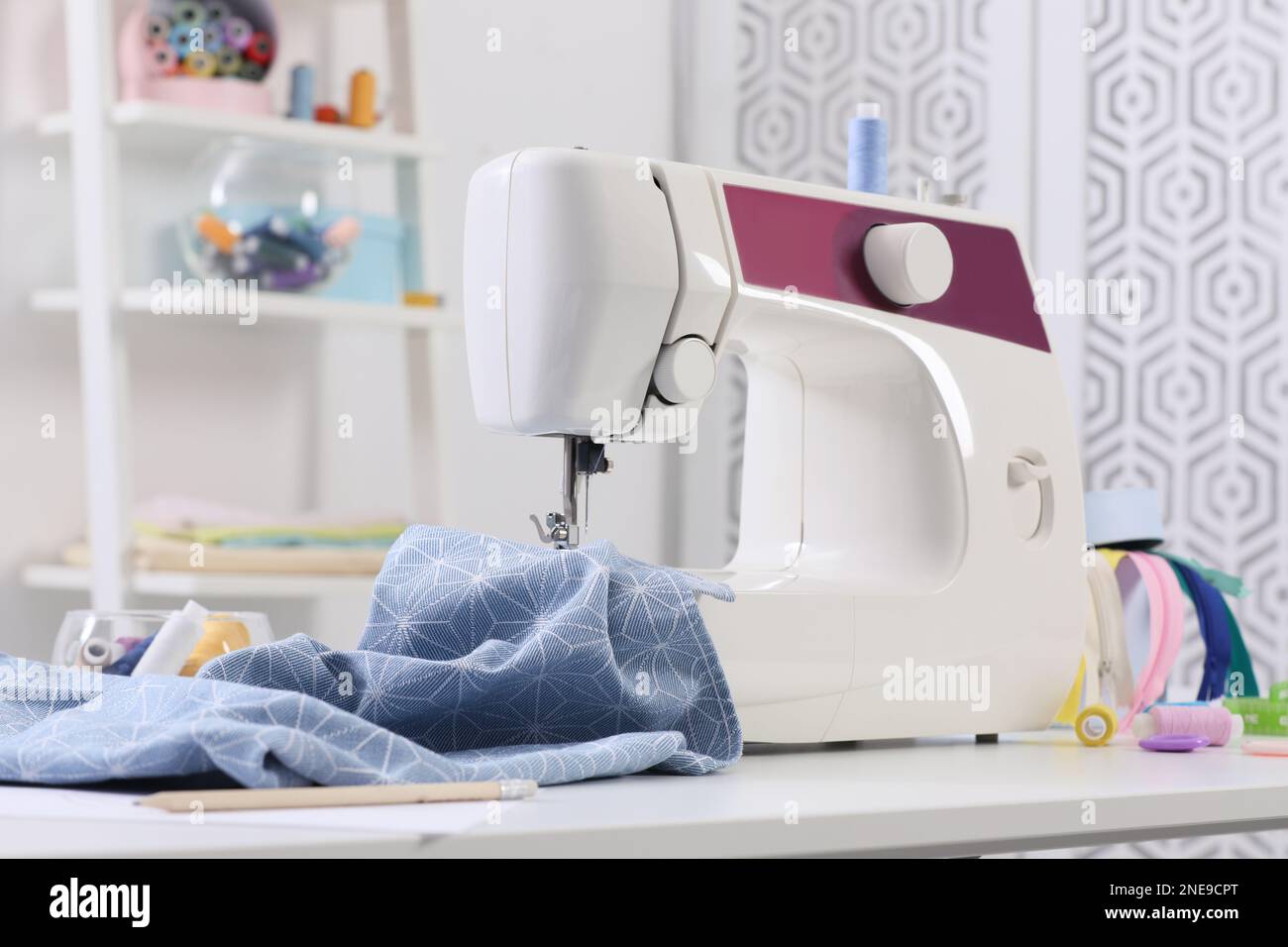 Modern sewing machine, fabric and accessories on table indoors Stock ...