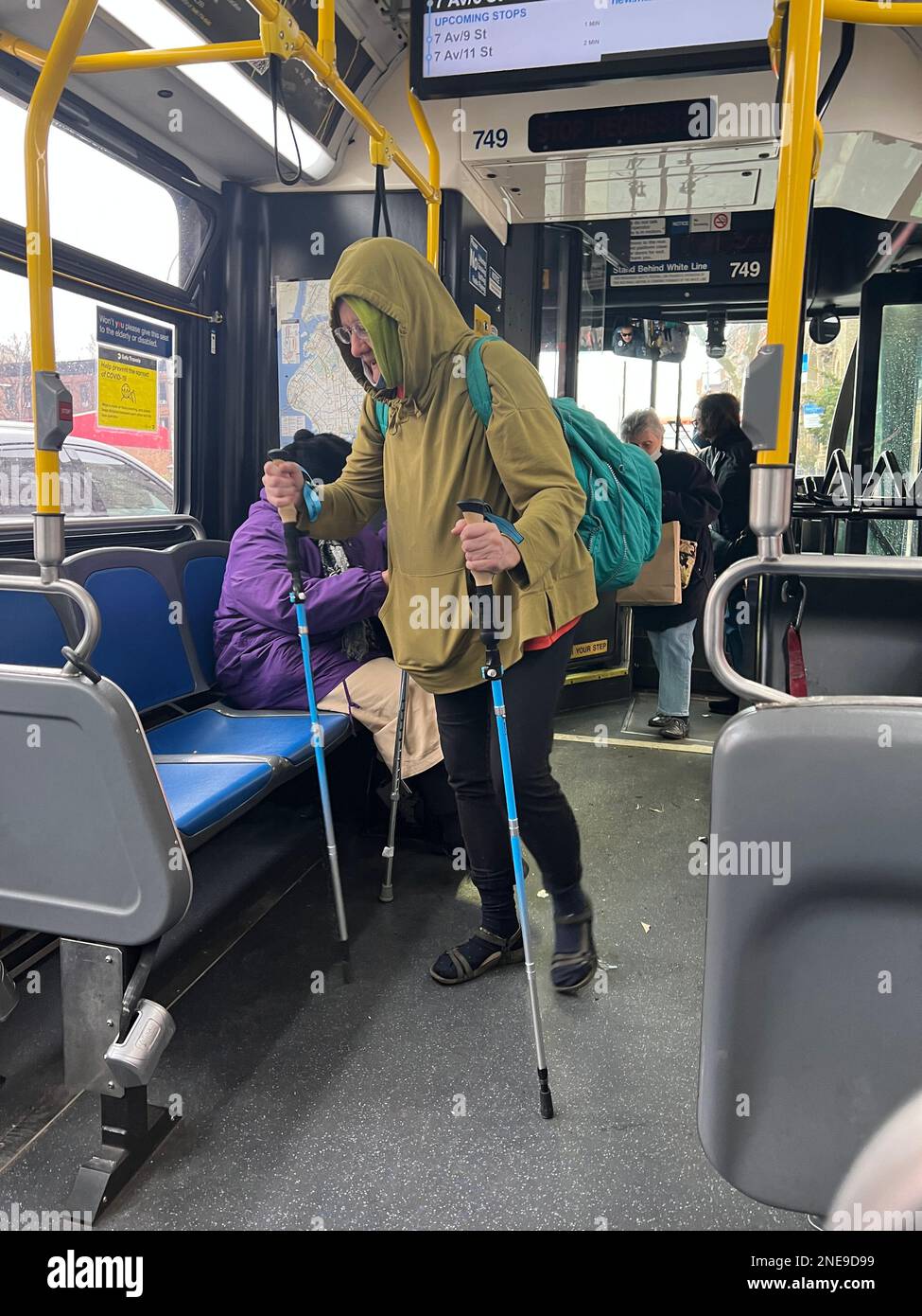 Older woman with walking sticks getting on a city bus in Brooklyn, New ...