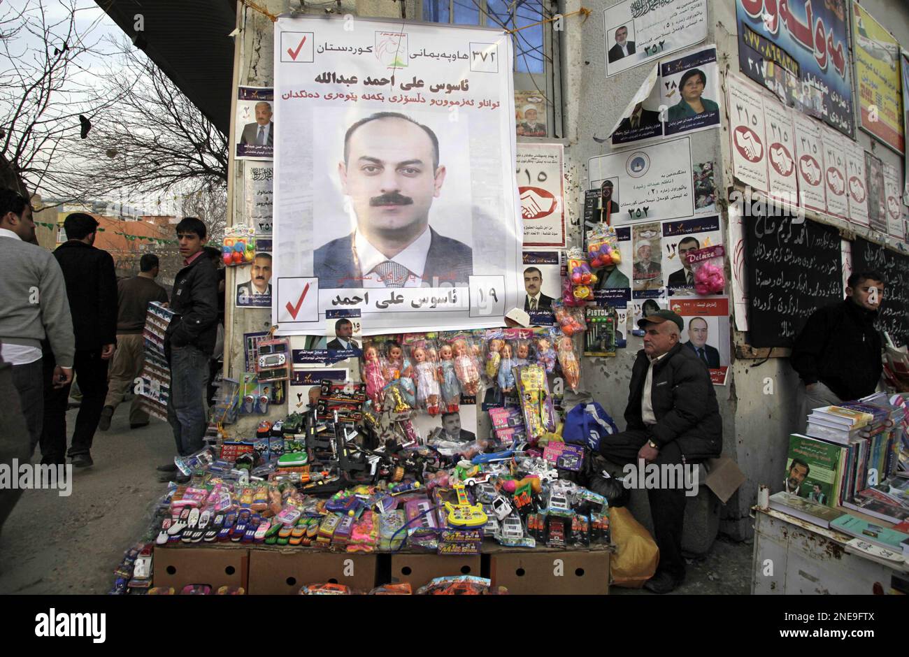 A vendor's stall sits below a campaign poster for Kurdish alliance ...