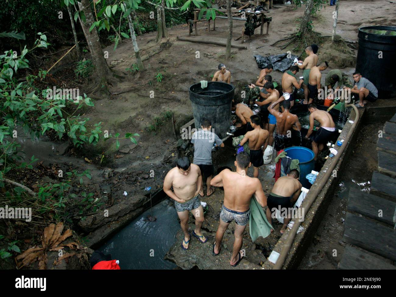 Soldiers take a shower while others washe their uniforms at a barrack ...