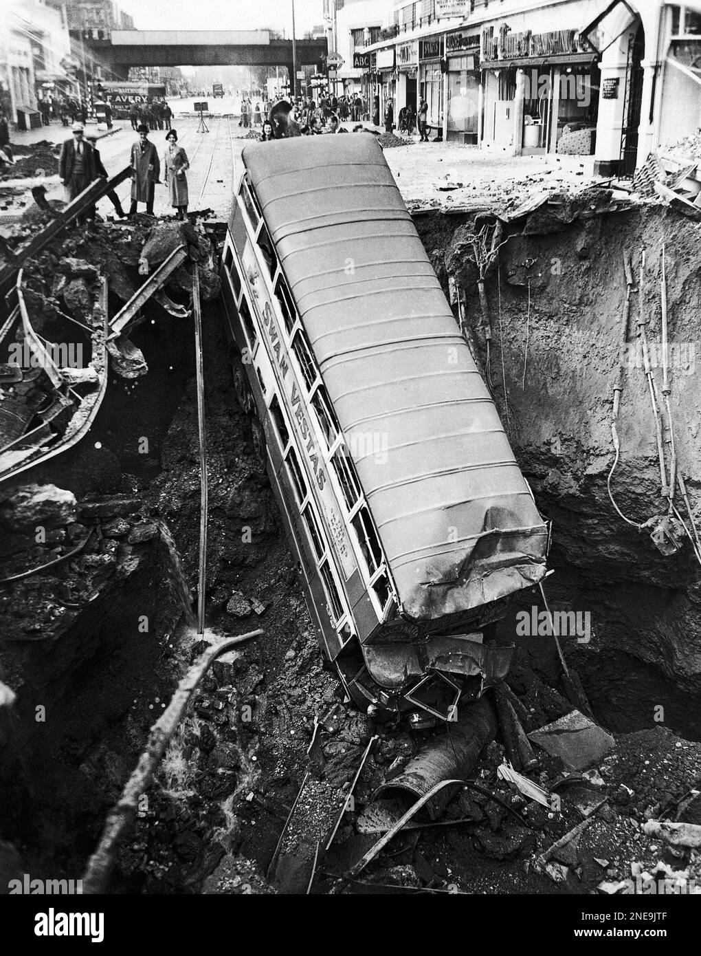 This unusual view of a bus nosed into a huge bomb crater in a London ...