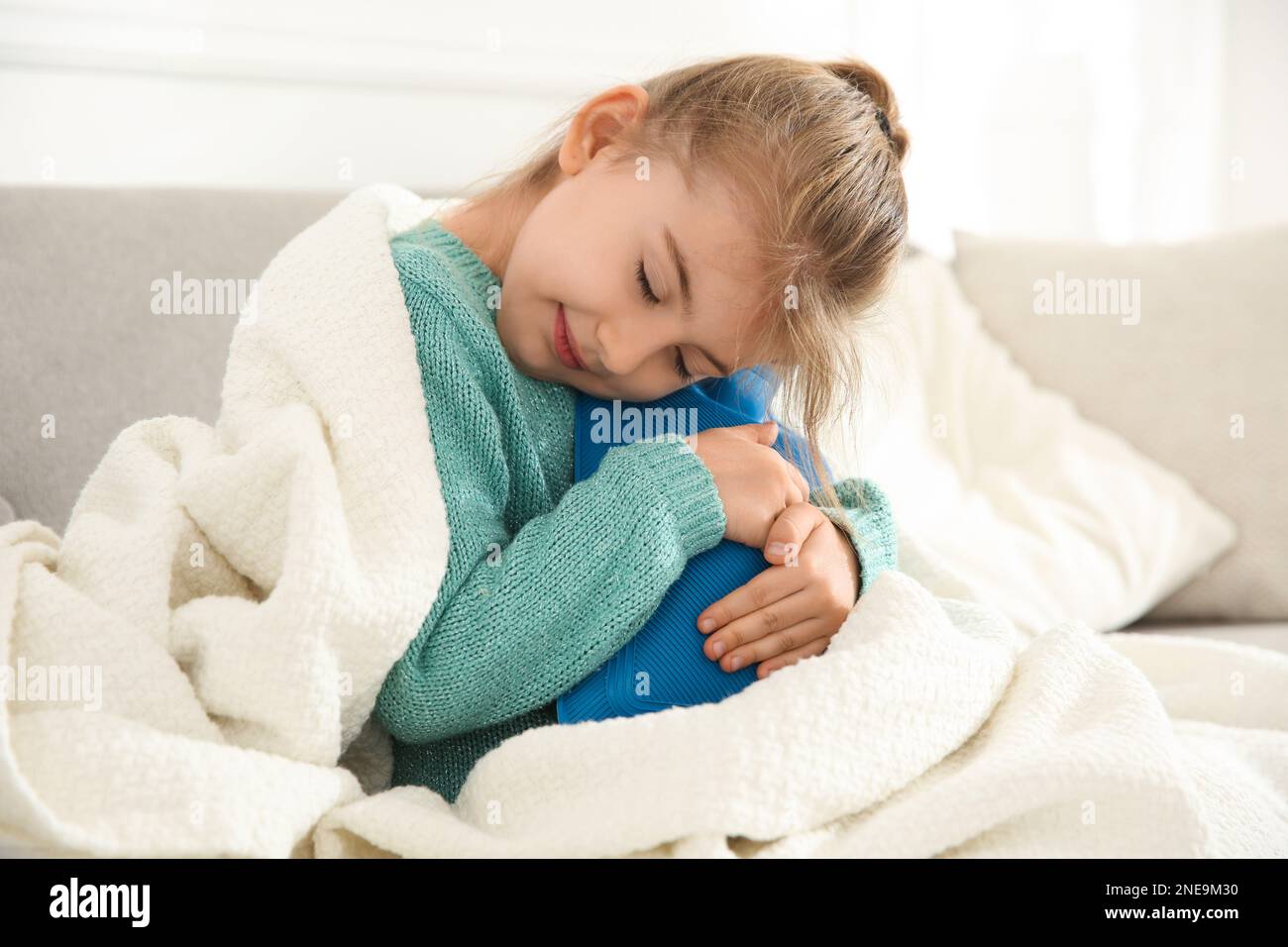Ill girl with hot water bottle suffering from cold at home Stock Photo ...