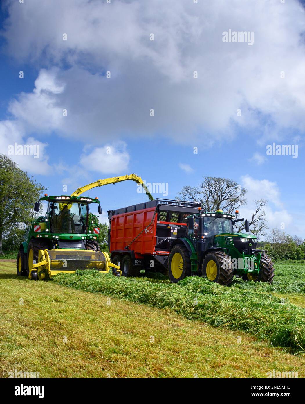 John Deere self propelled forager filling a trailer, towed by a John ...