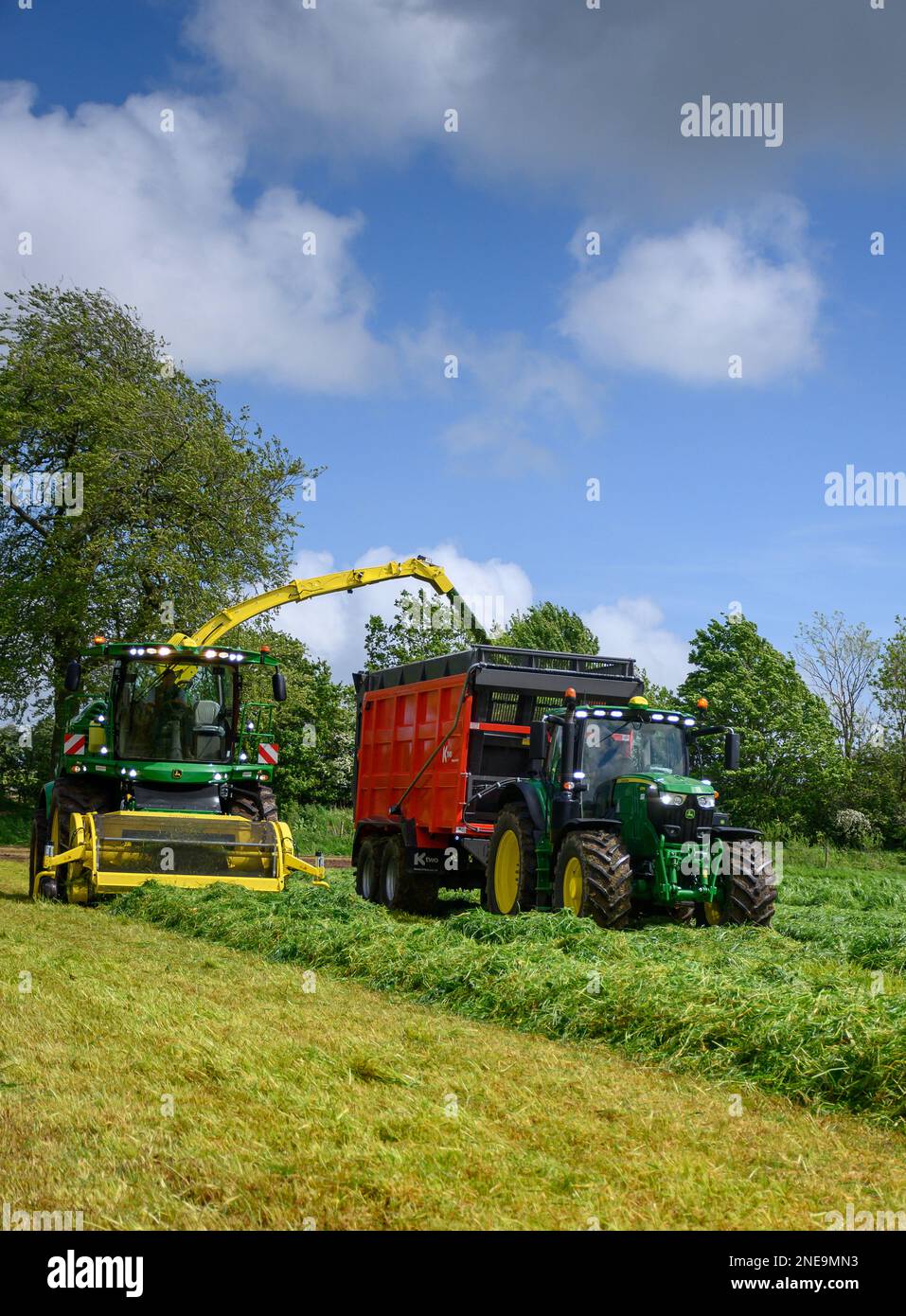 John Deere self propelled forager filling a trailer, towed by a John ...